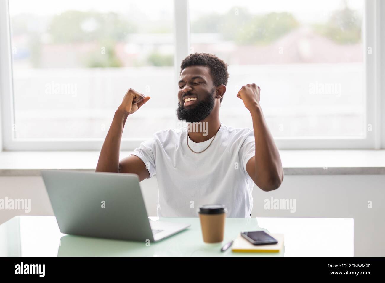 Excited euphoric african winner looking at laptop celebrating online ...