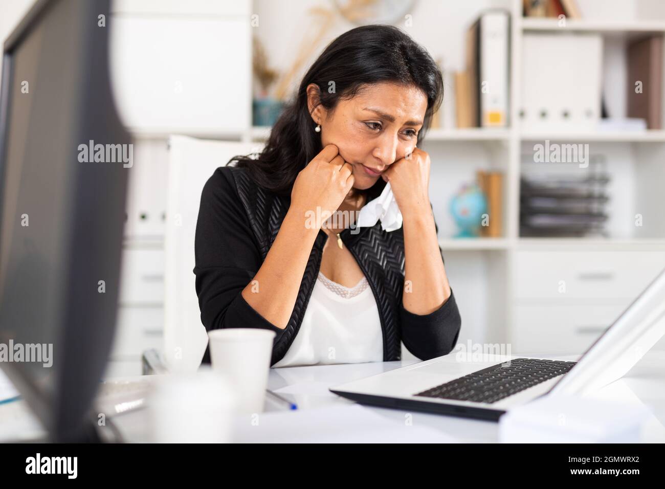 Upset peruvian business woman crying at her workplace in modern office ...