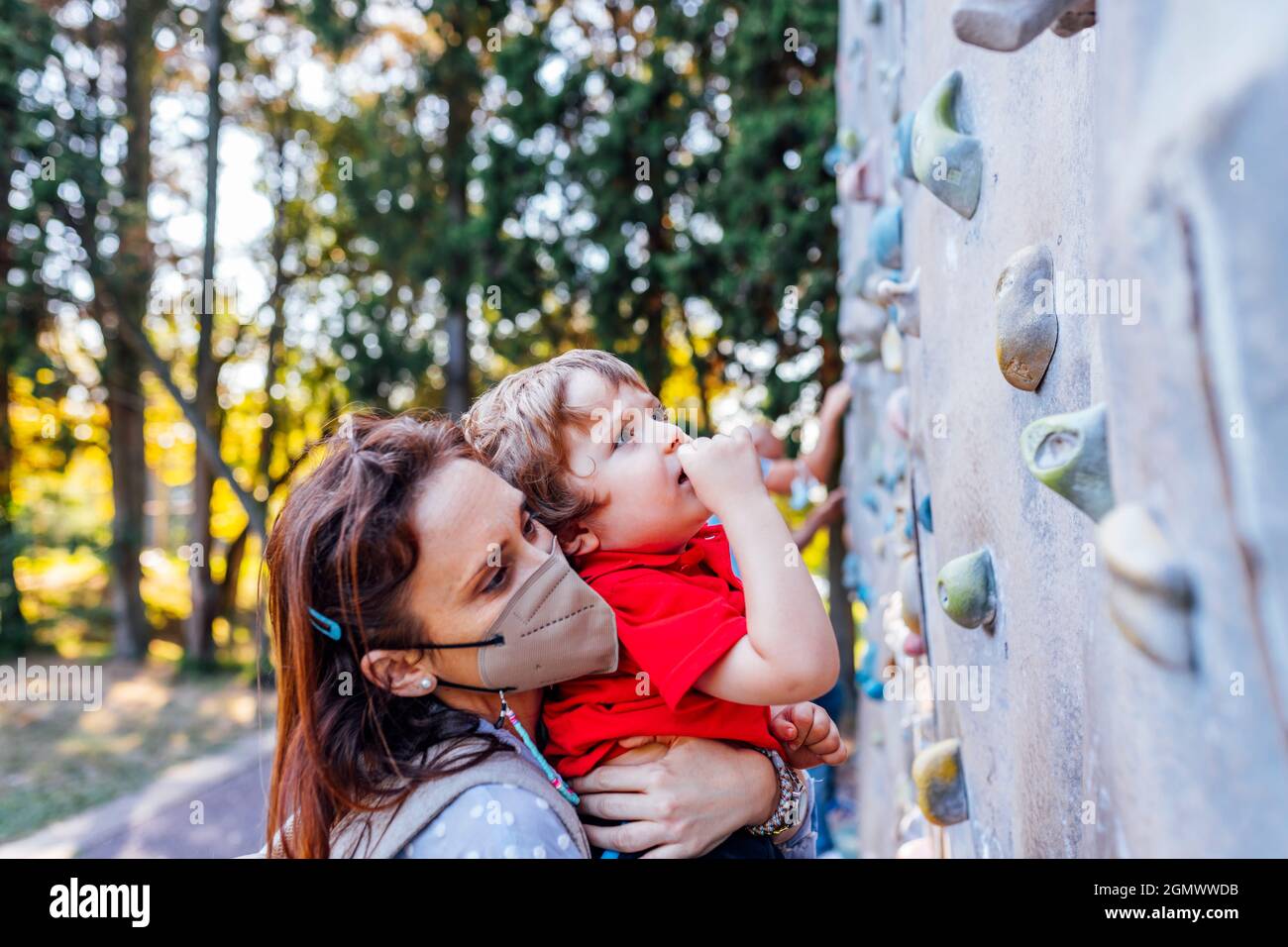 three-year-old boy assisted by his young adult mother learning to climb ...