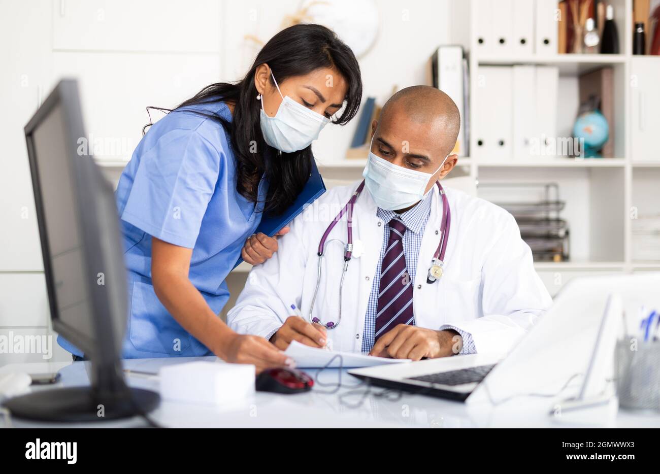 Doctor and nurse in protective medical mask check patient data in ...