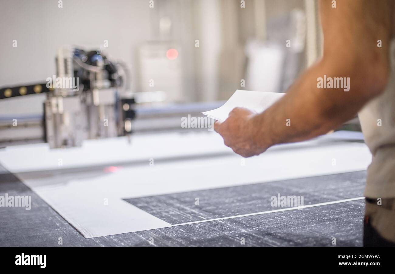 Factory worker technician works on large CNC digital cutter machine for ...