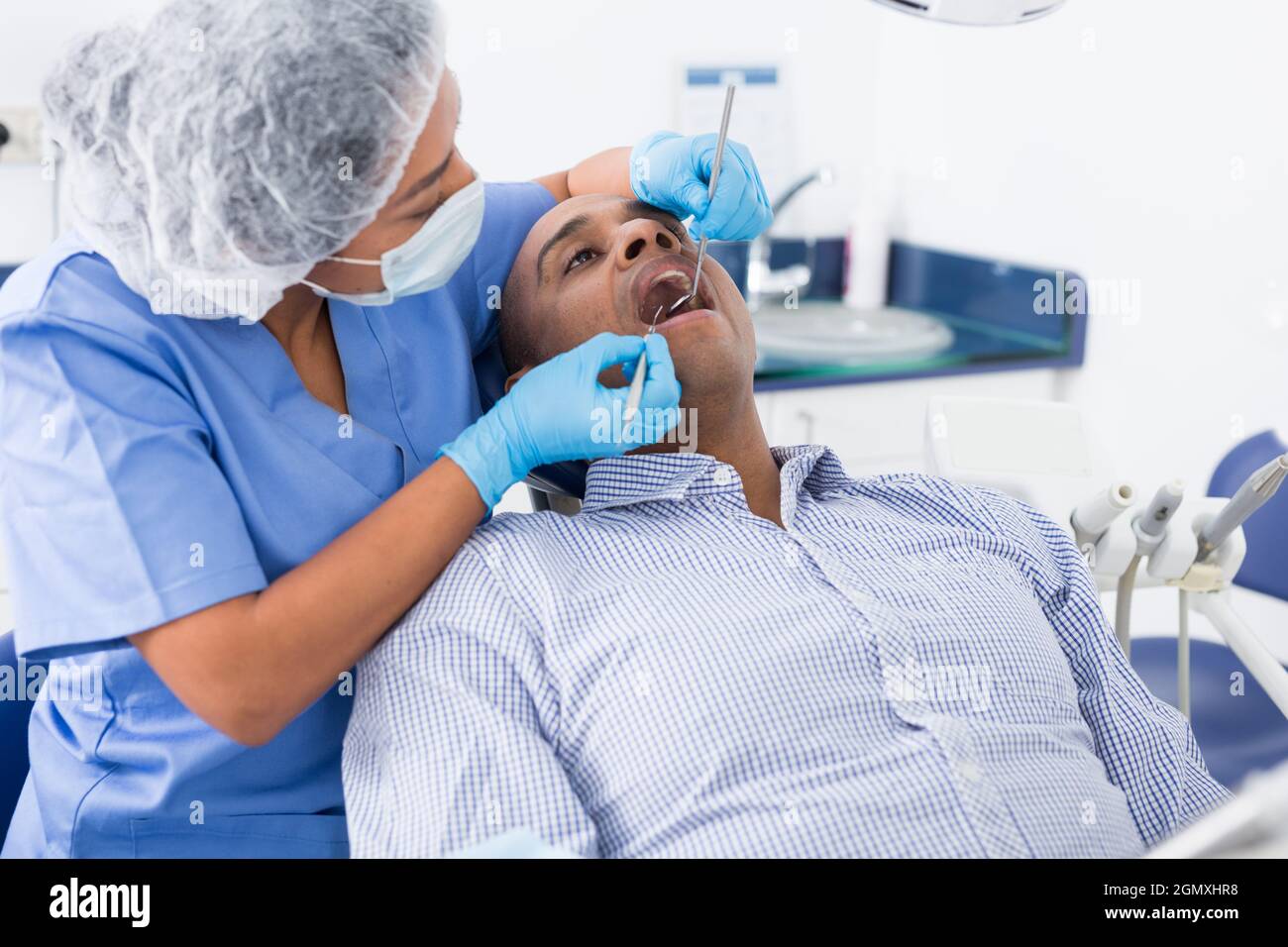 Dentist professional filling teeth for man patient sitting in medical ...