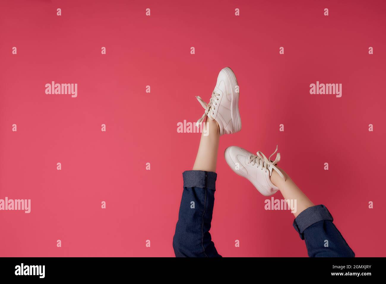 woman in white sneakers legs pink background posing Stock Photo - Alamy