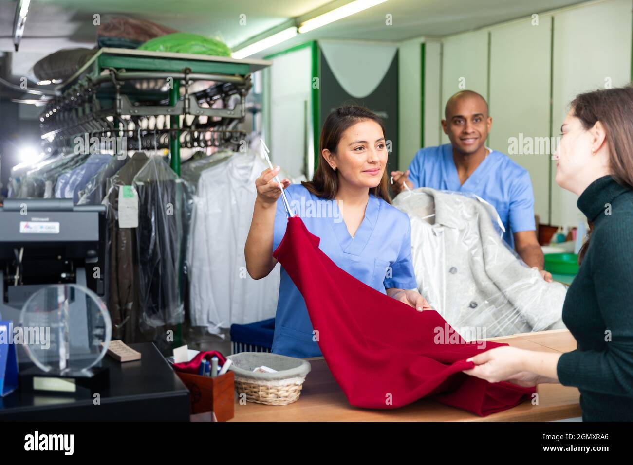 Laundry workers giving clean clothes to client Stock Photo - Alamy