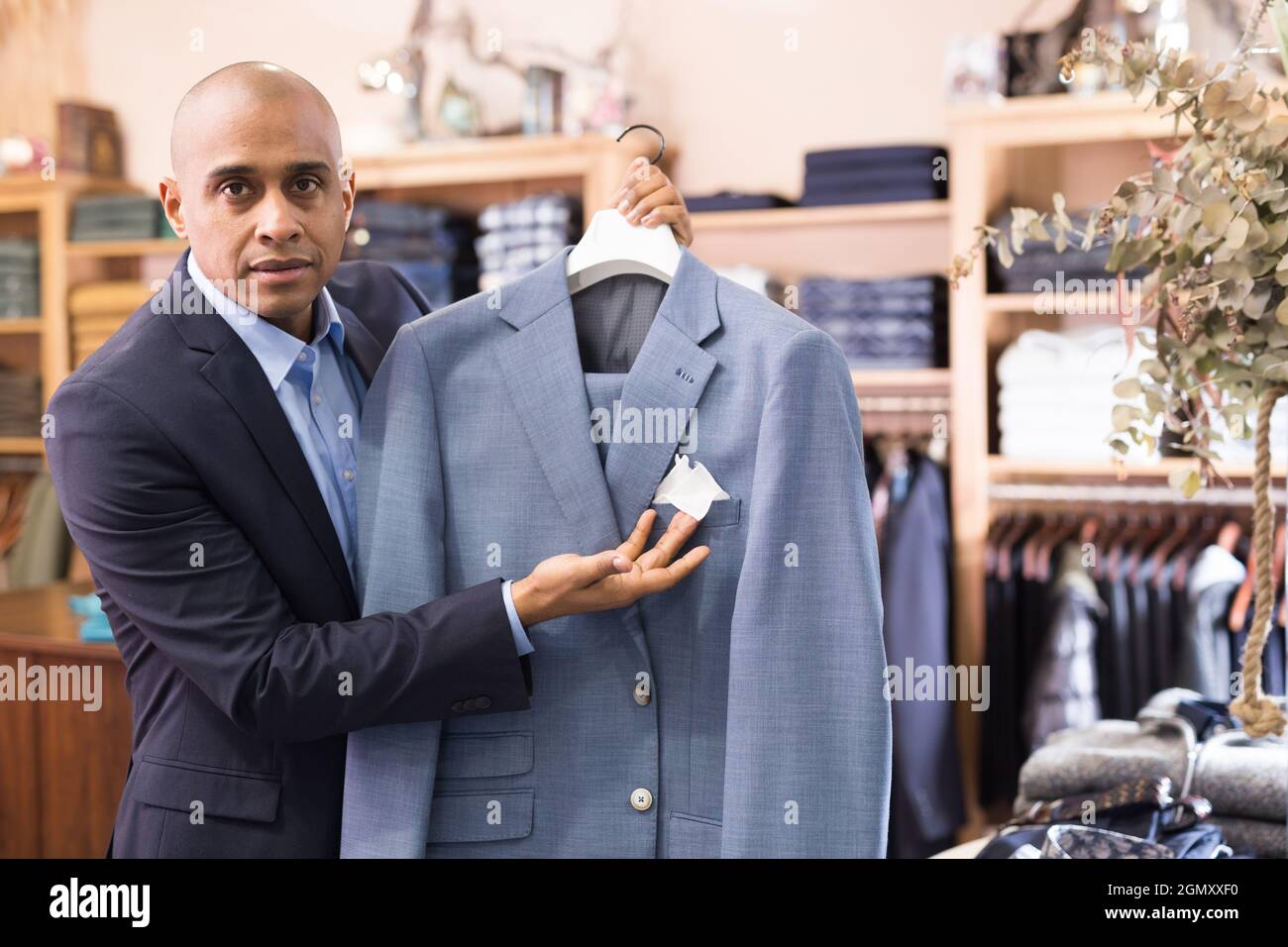 Portrait of confident salesman demonstrating suits in apparel shop ...