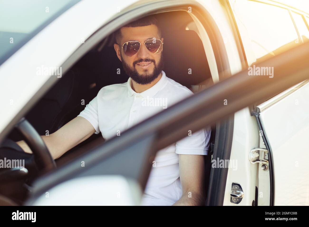 Happy owner, handsome bearded young man, in white t-shirt, sits relaxed ...