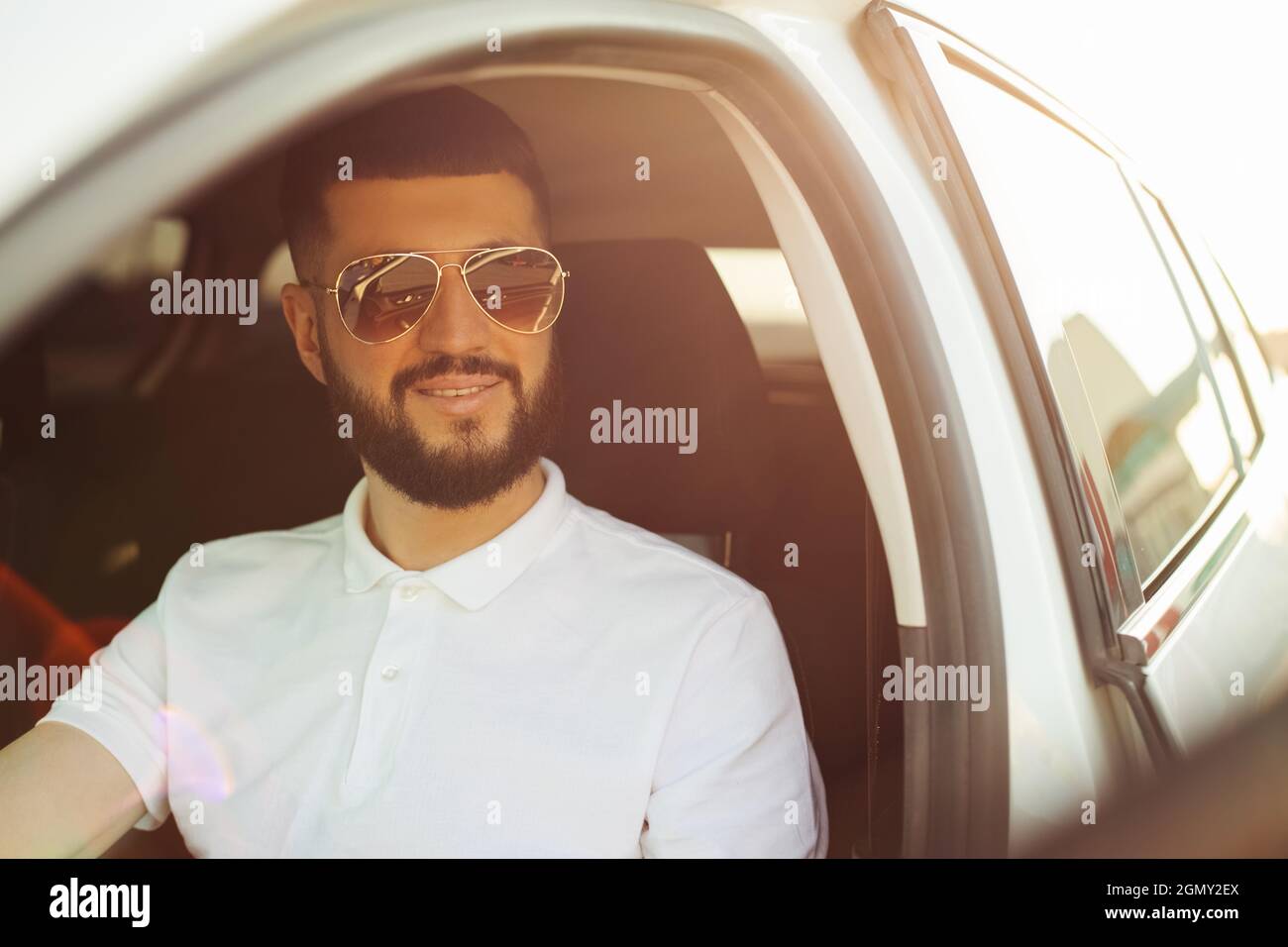 Happy owner, handsome bearded young man, in white t-shirt, sits relaxed ...