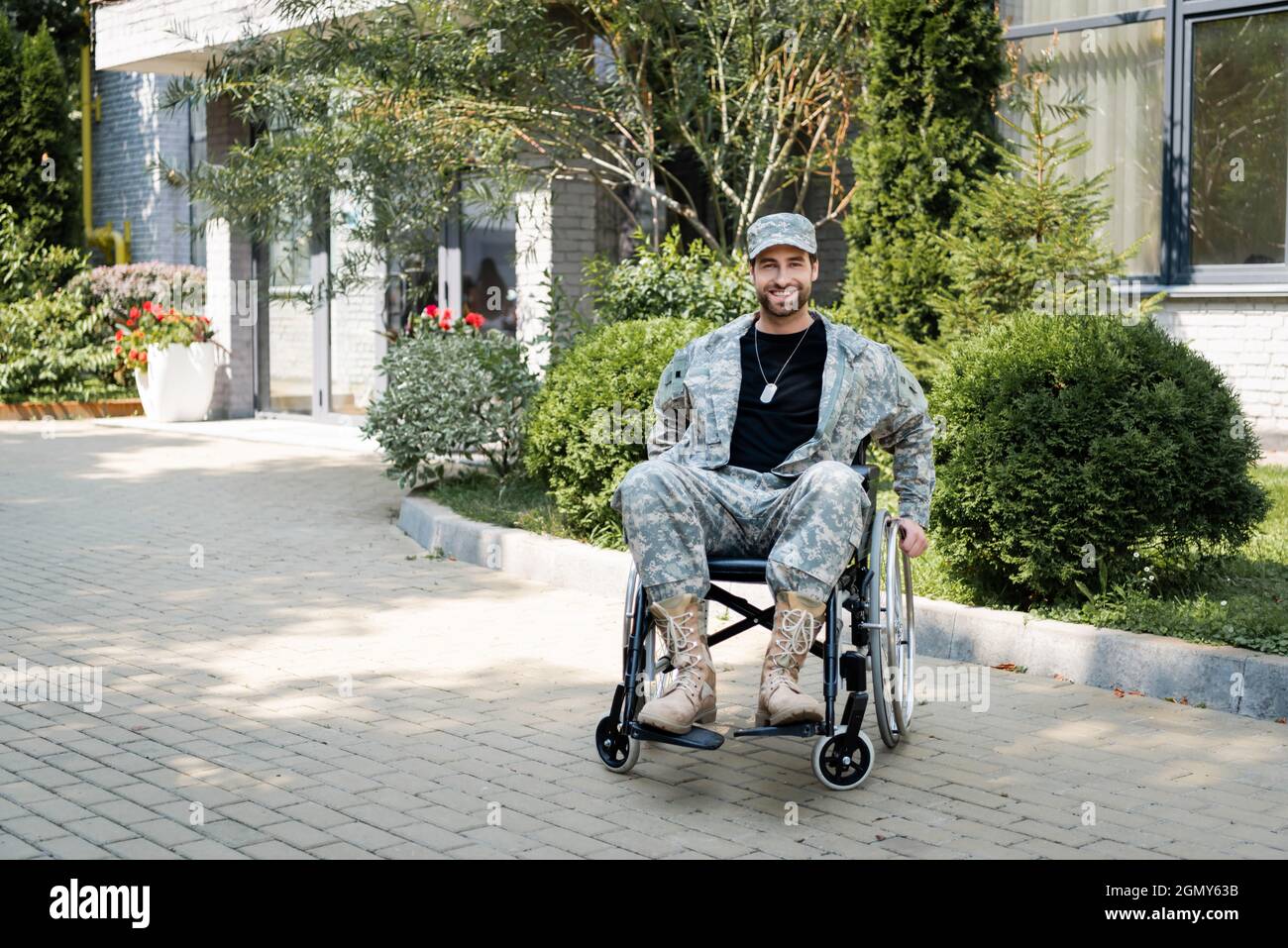 positive disabled soldier in wheelchair smiling at camera outdoors ...