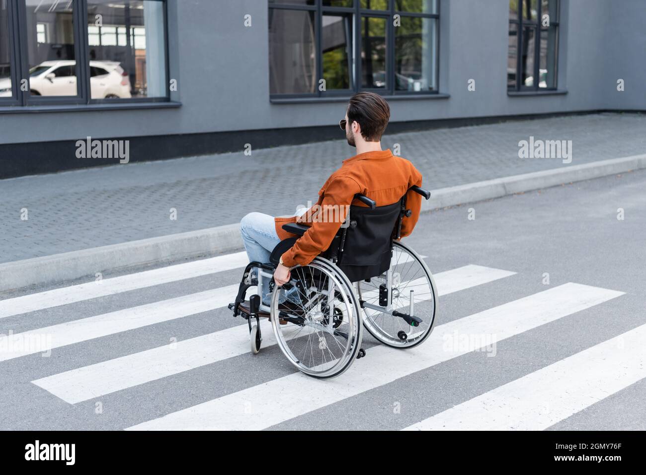 young disabled man crossing road in wheelchair Stock Photo - Alamy