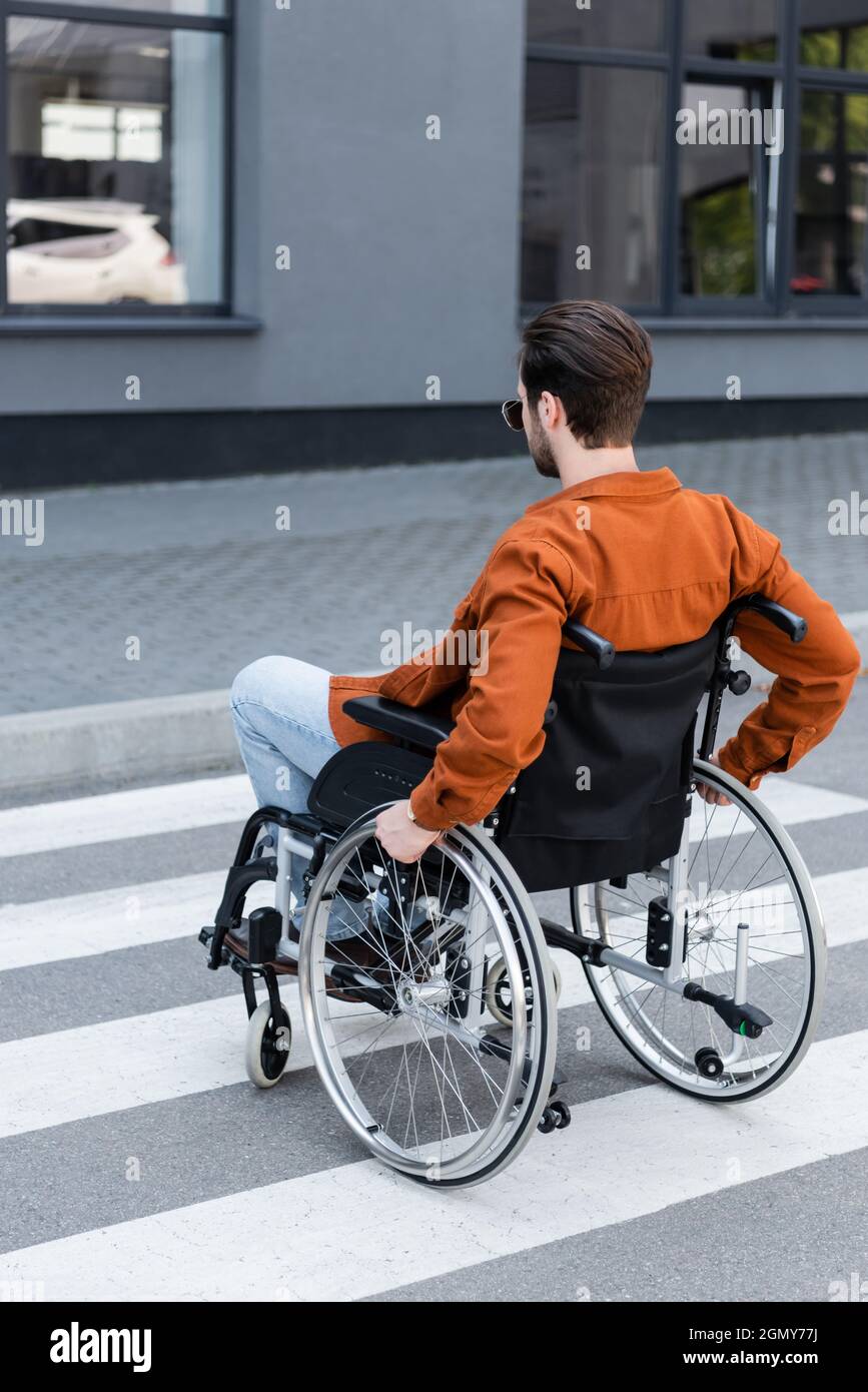 handicapped man moving on crosswalk in wheelchair Stock Photo - Alamy