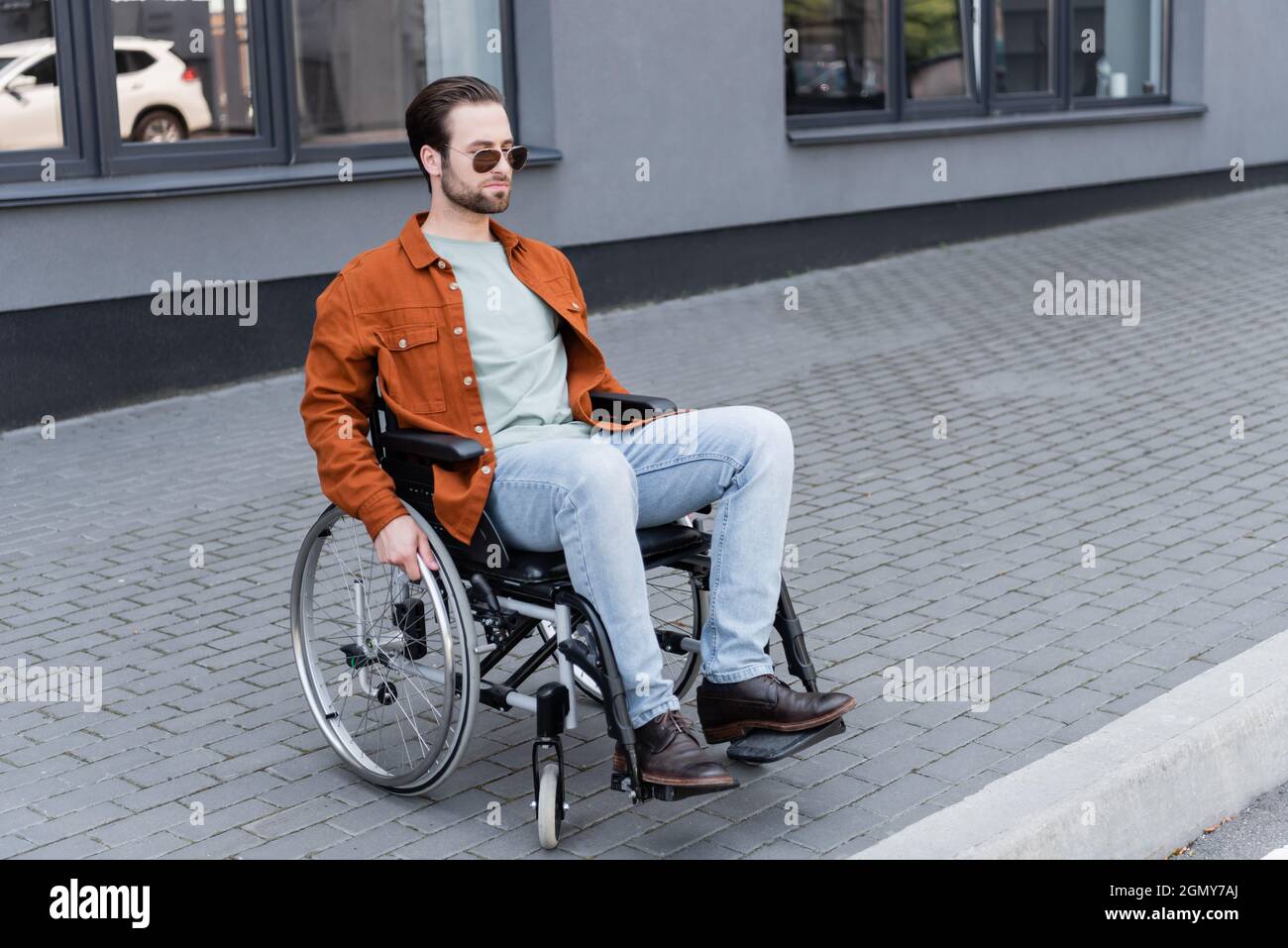 young handicapped man in wheelchair on pavement with border in city ...