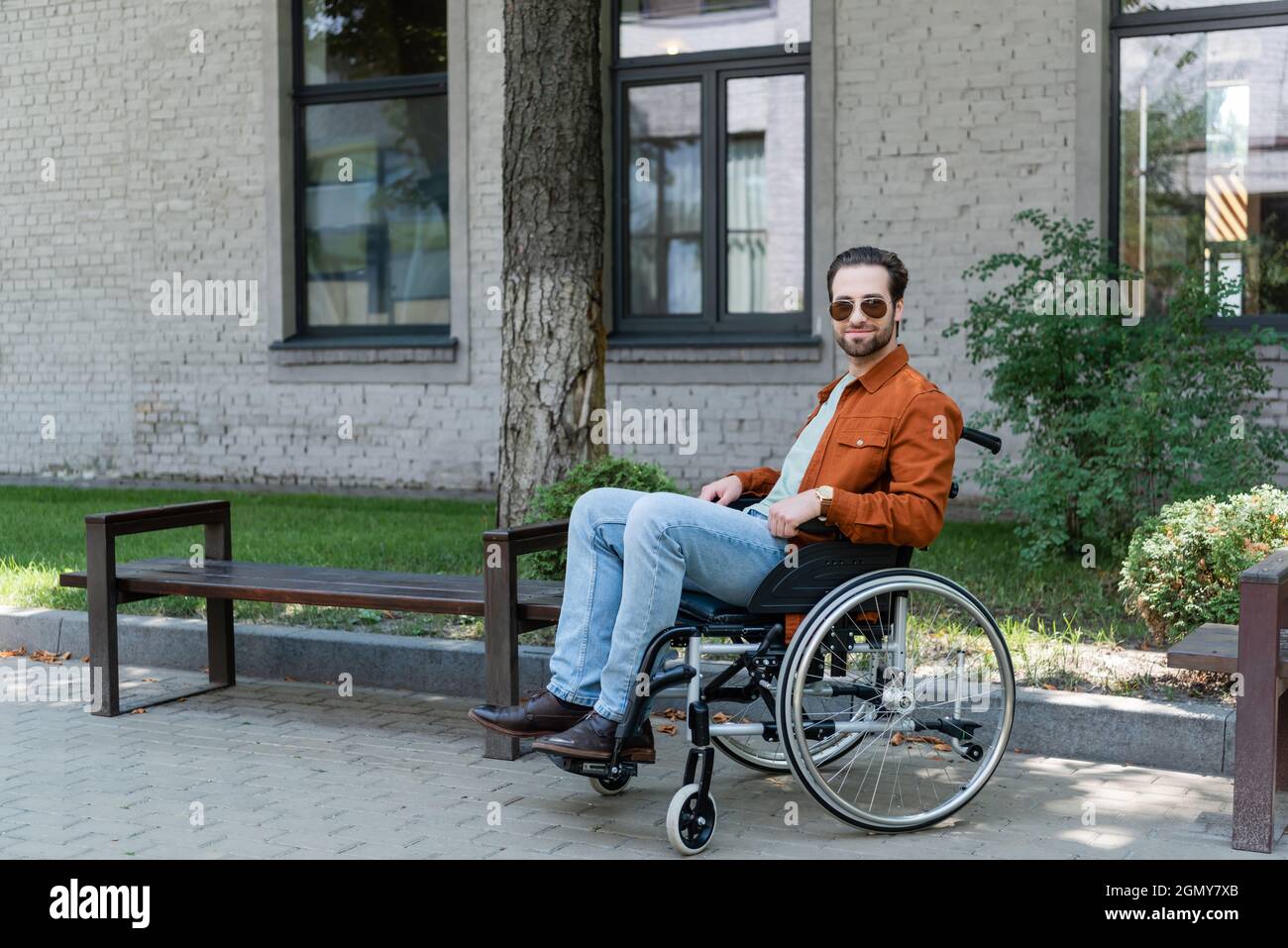 young disabled man in wheelchair smiling at camera on urban street ...
