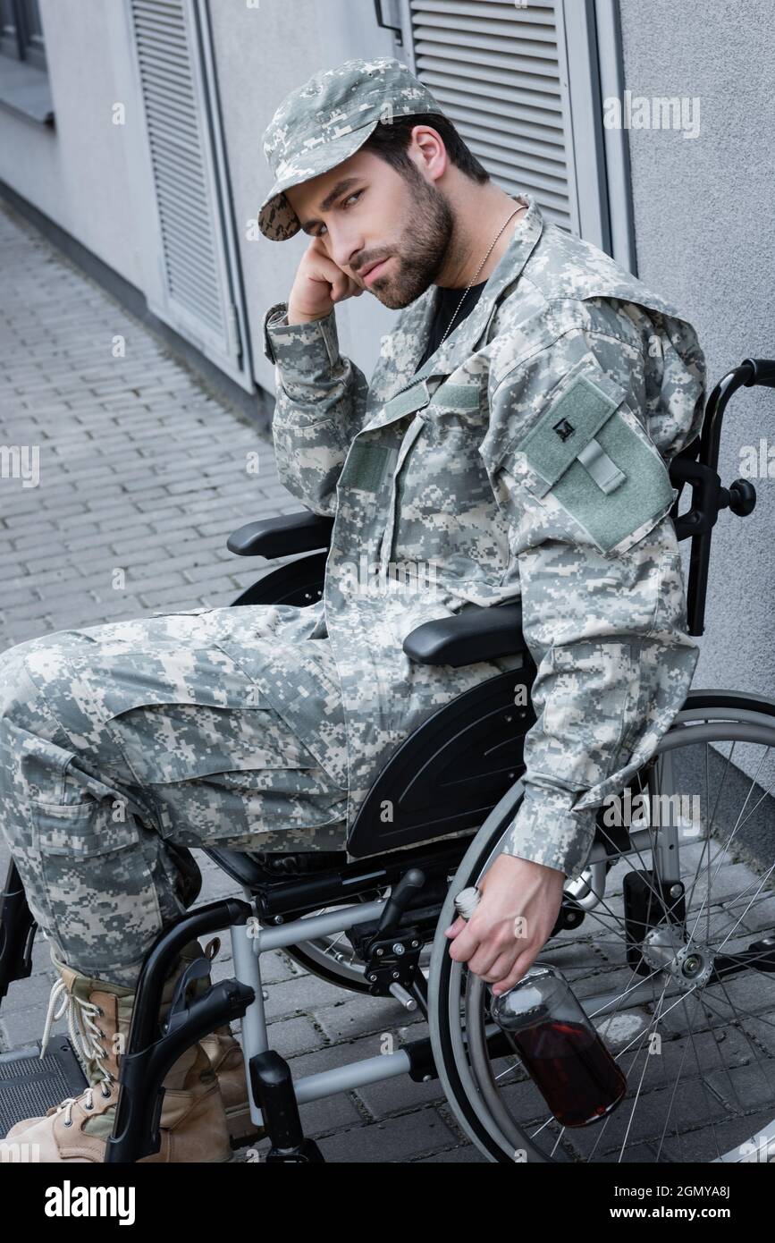 disabled soldier looking at camera while sitting in wheelchair on urban ...