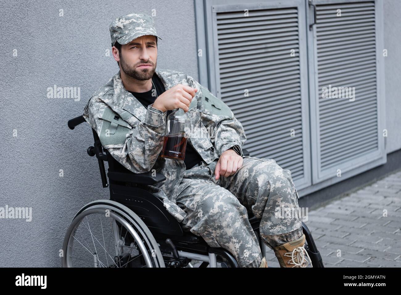 depressed and disabled military man sitting in wheelchair with bottle ...