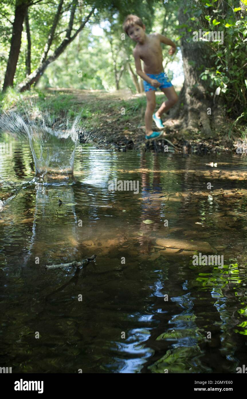 Little boy throwing pebbles into the water. Holidays where kids can go ...