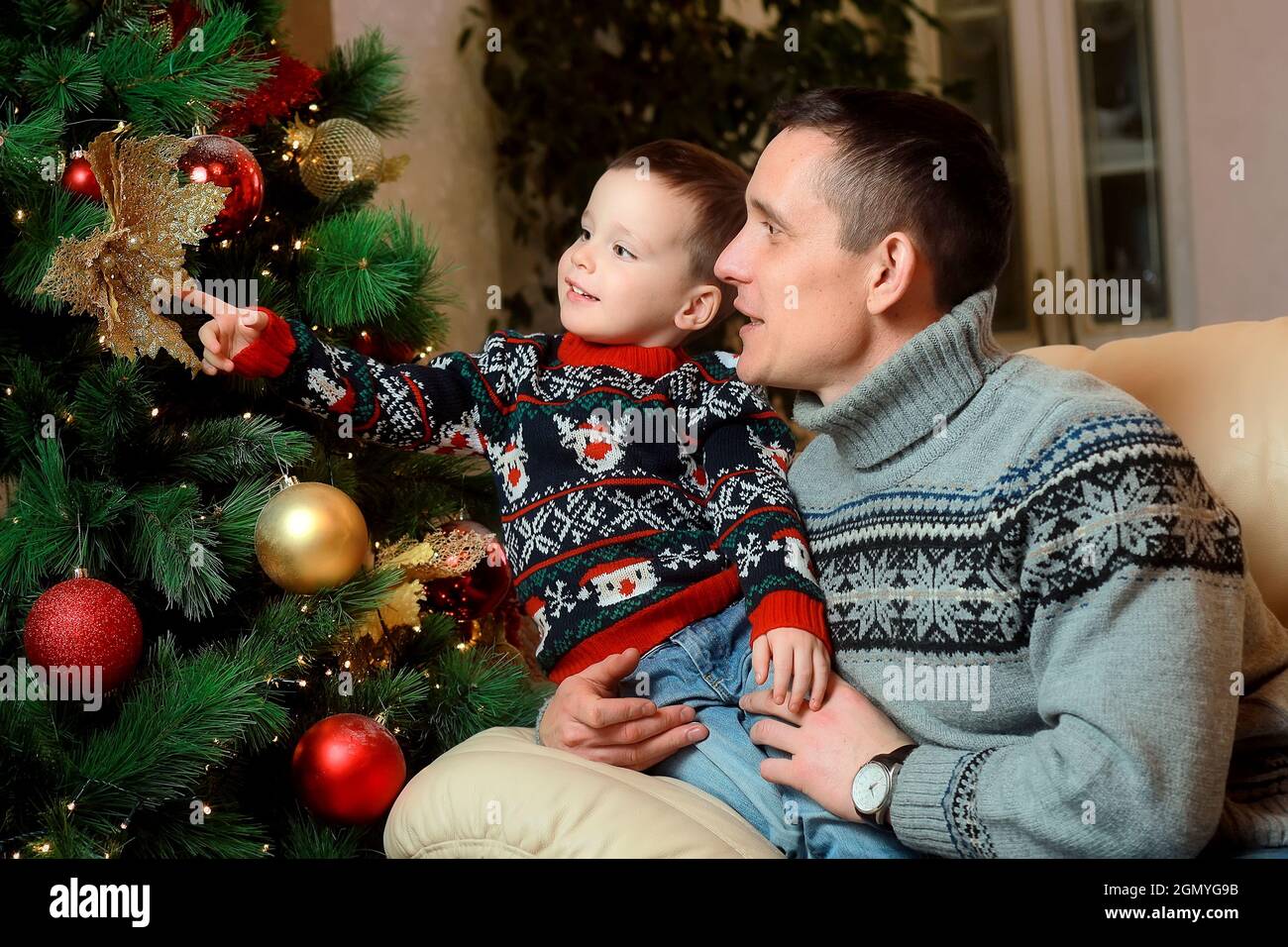 Portrait of a father with a young son near a Christmas tree with ...