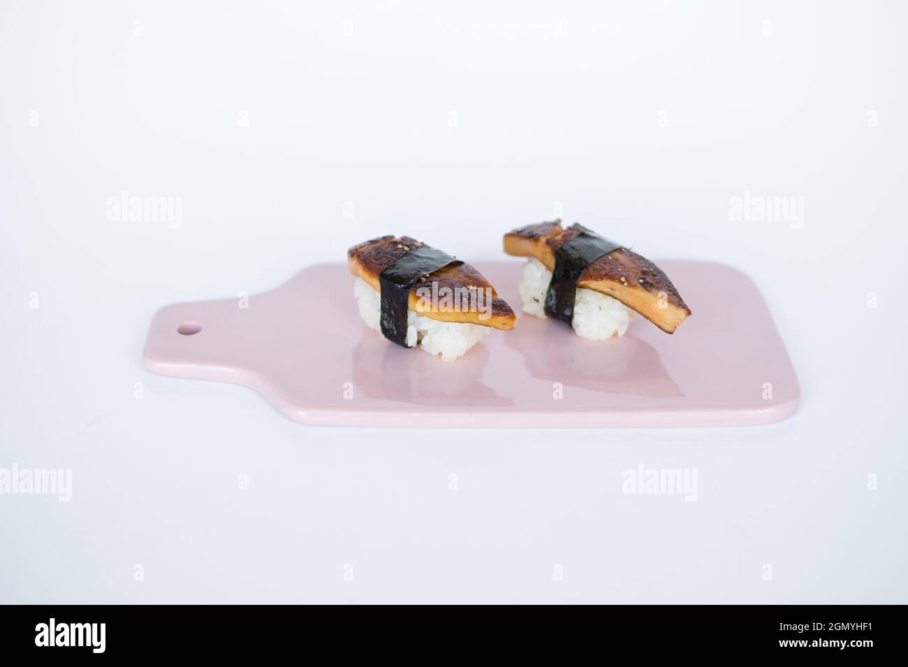 Japanese Sushi - Two Unagi Nigiri Sushi served on light pink board. Eel Sushi. Sushi pieces ...