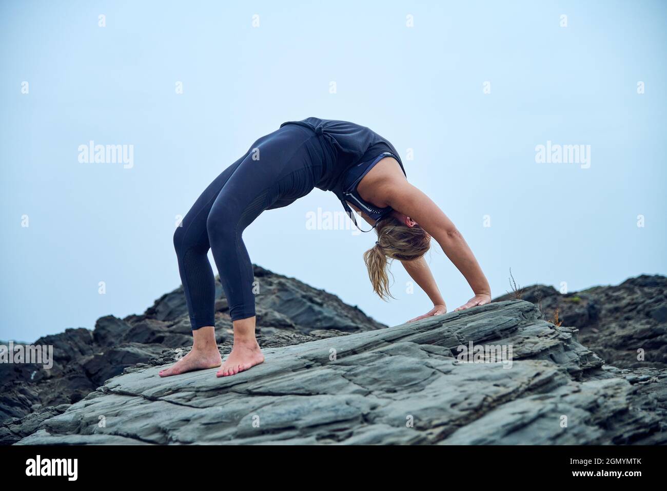 Native American woman from Spain practicing yoga in a rocky area on a ...