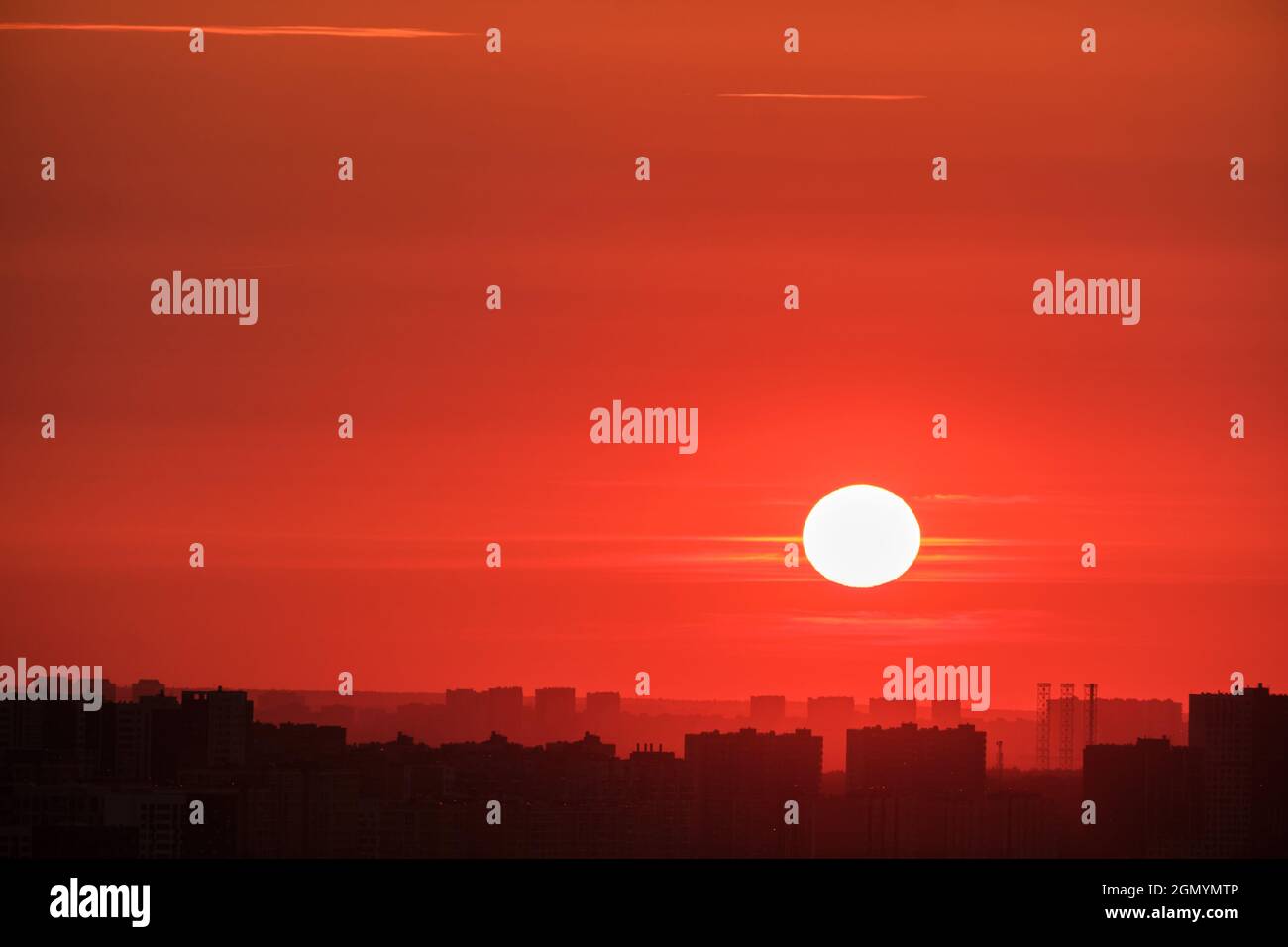 The big red sun sets behind the roofs of houses at sunset, timelapse ...