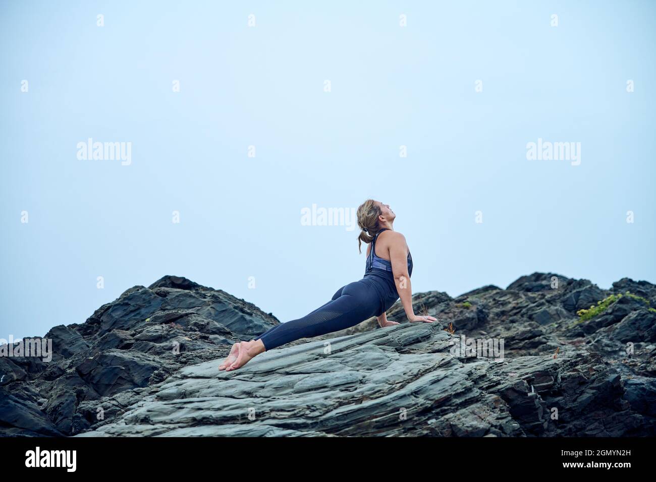 Native American woman from Spain practicing yoga in a rocky area on a ...