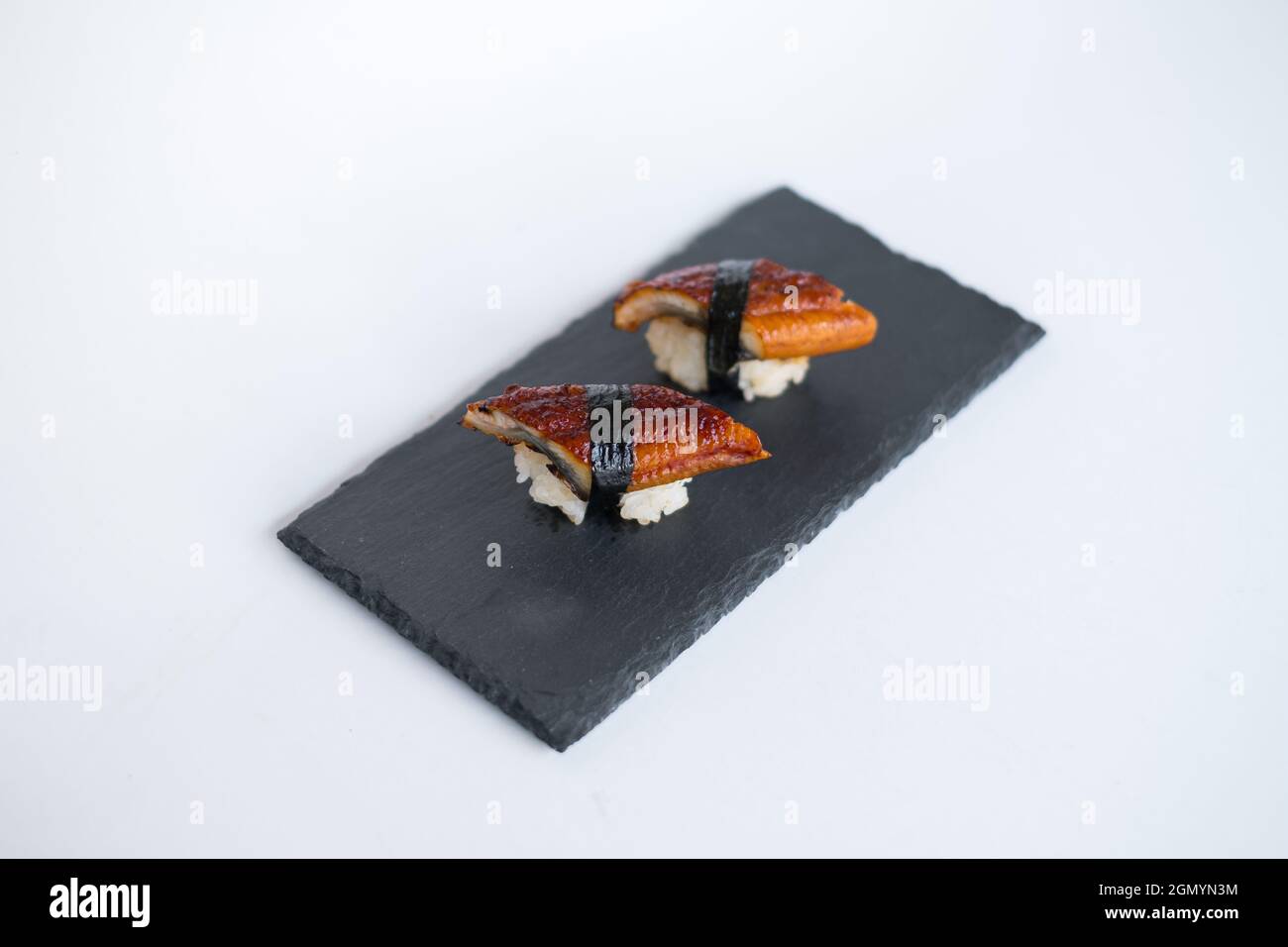 Japanese Sushi - Two Unagi Nigiri Sushi served on a black stone board. Eel Sushi. Sushi pieces ...