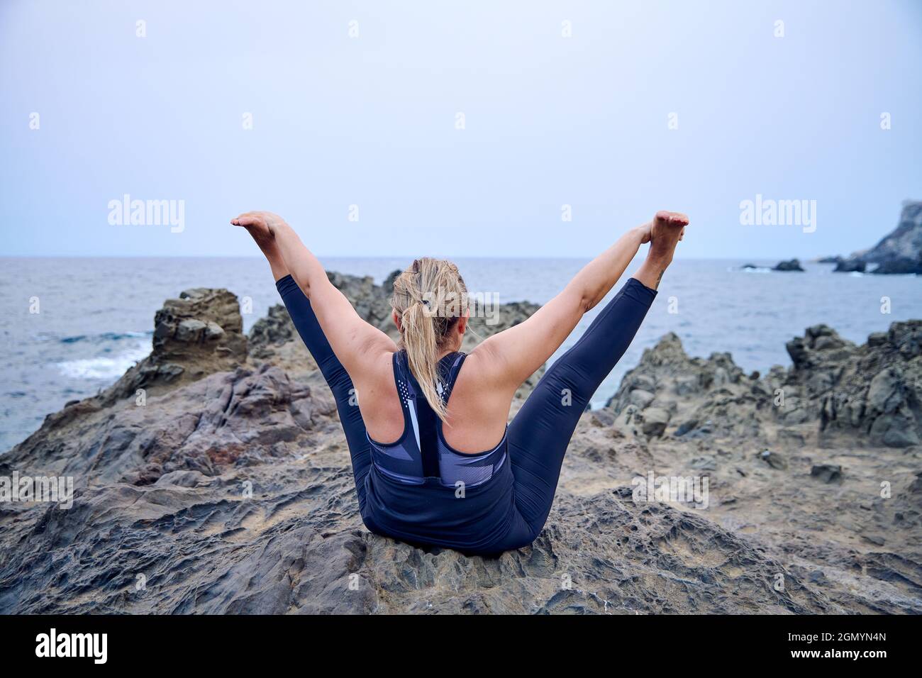 Native American woman from Spain practicing yoga at the beach on a ...