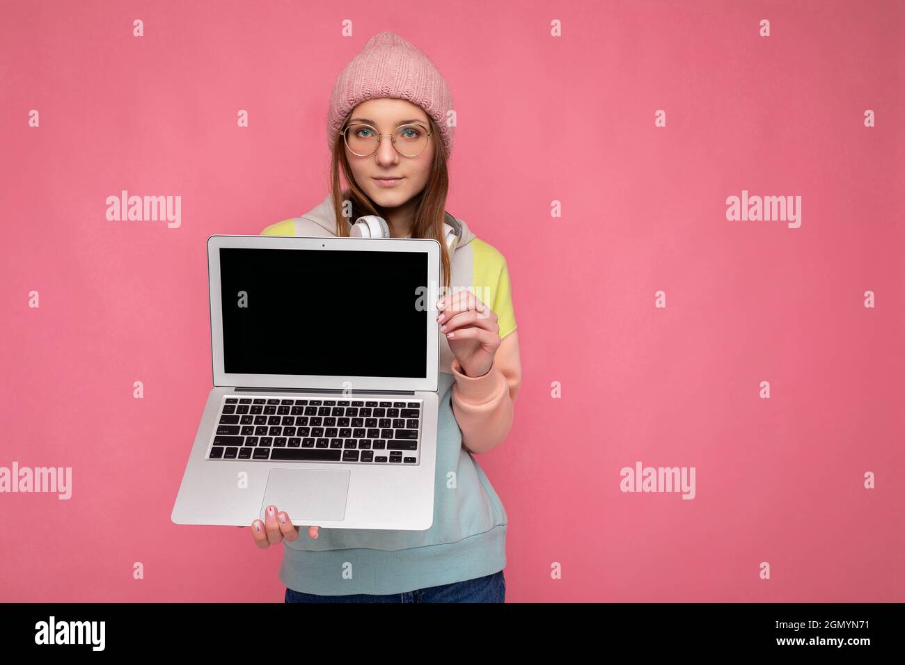 Pretty young woman wearing hat colorful sweater and glasses holding ...