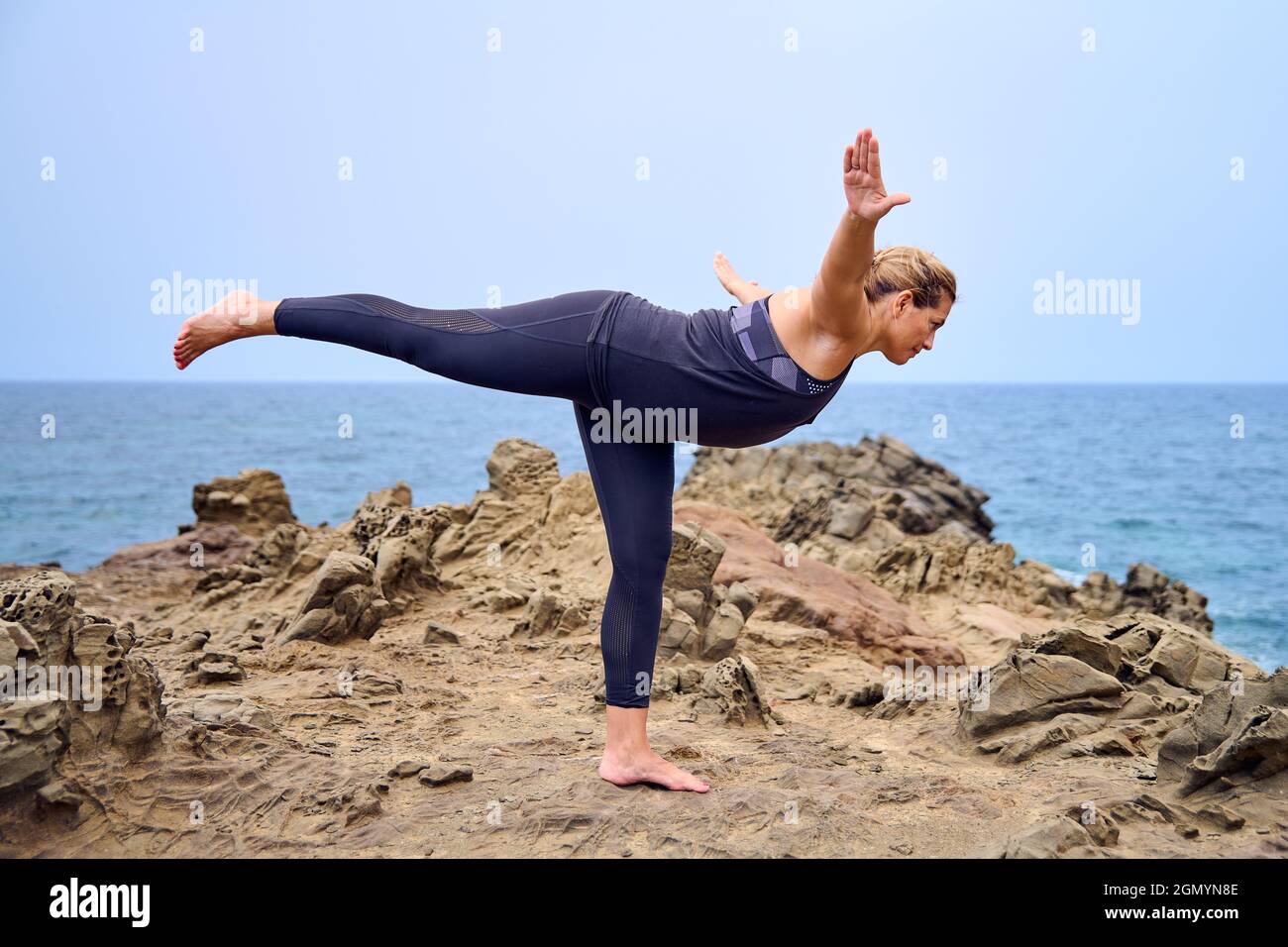 Native American woman from Spain practicing yoga at the beach on a ...