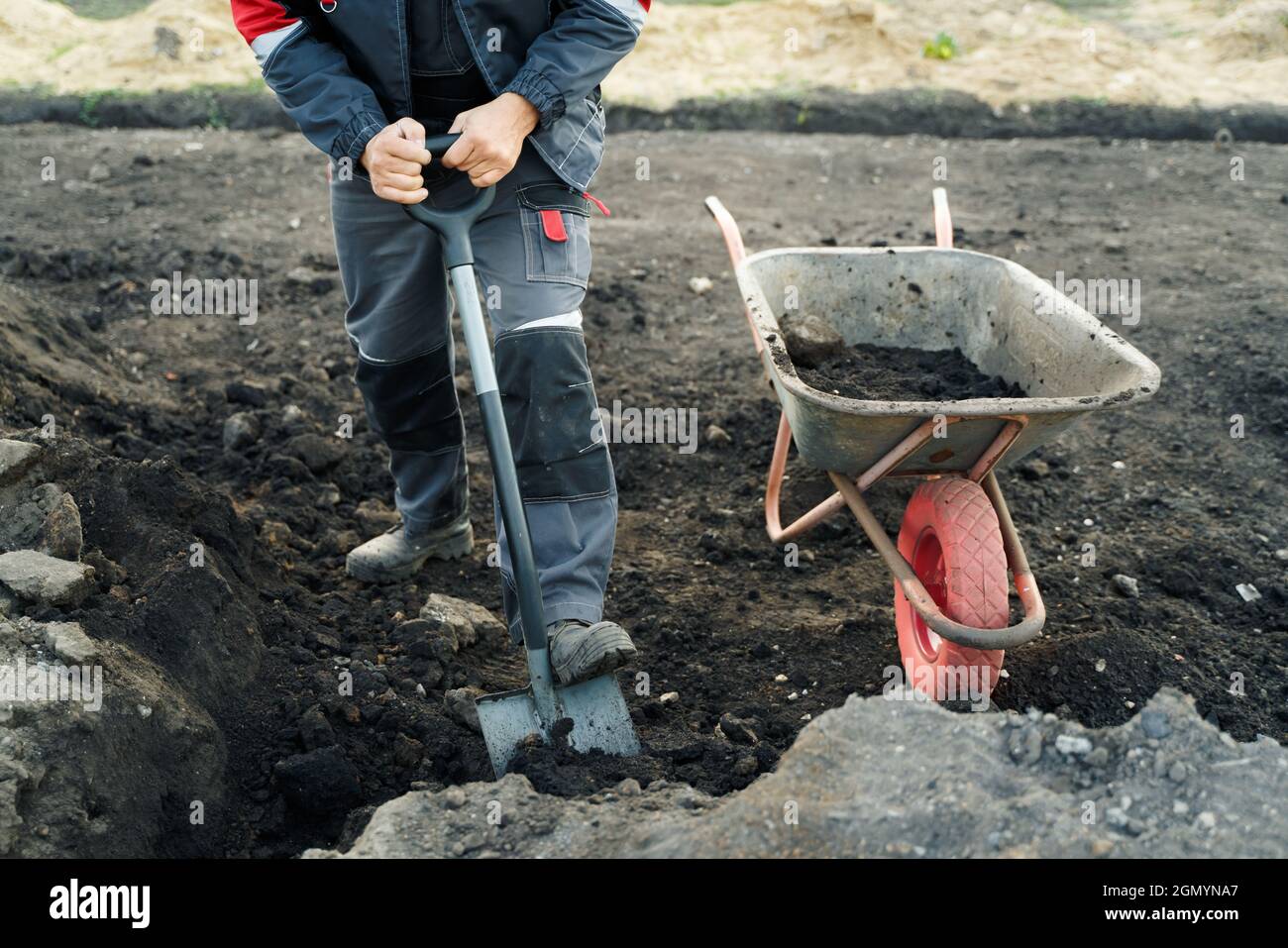 Working with garden tools, shovel and wheelbarrow on the site of a ...