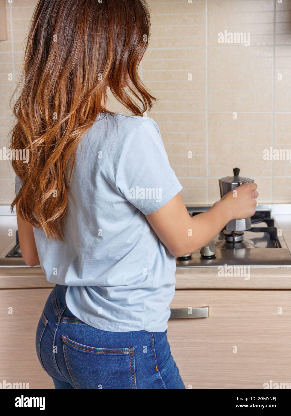 Unrecognizable young woman using stovetop moka coffee maker to brew ...