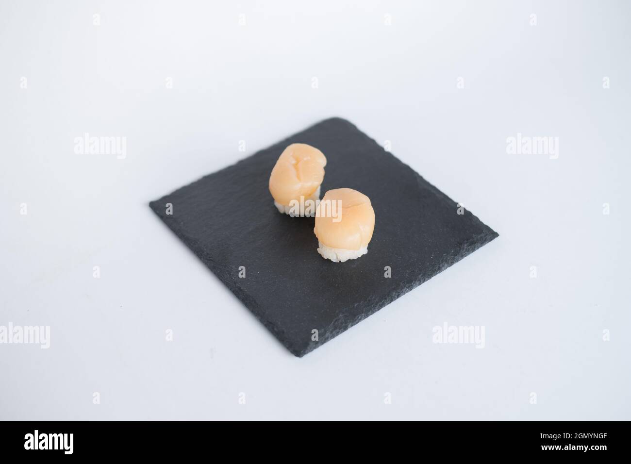 Two Nigiri Sushi with scallop served on black tray. Two sushi pieces ...