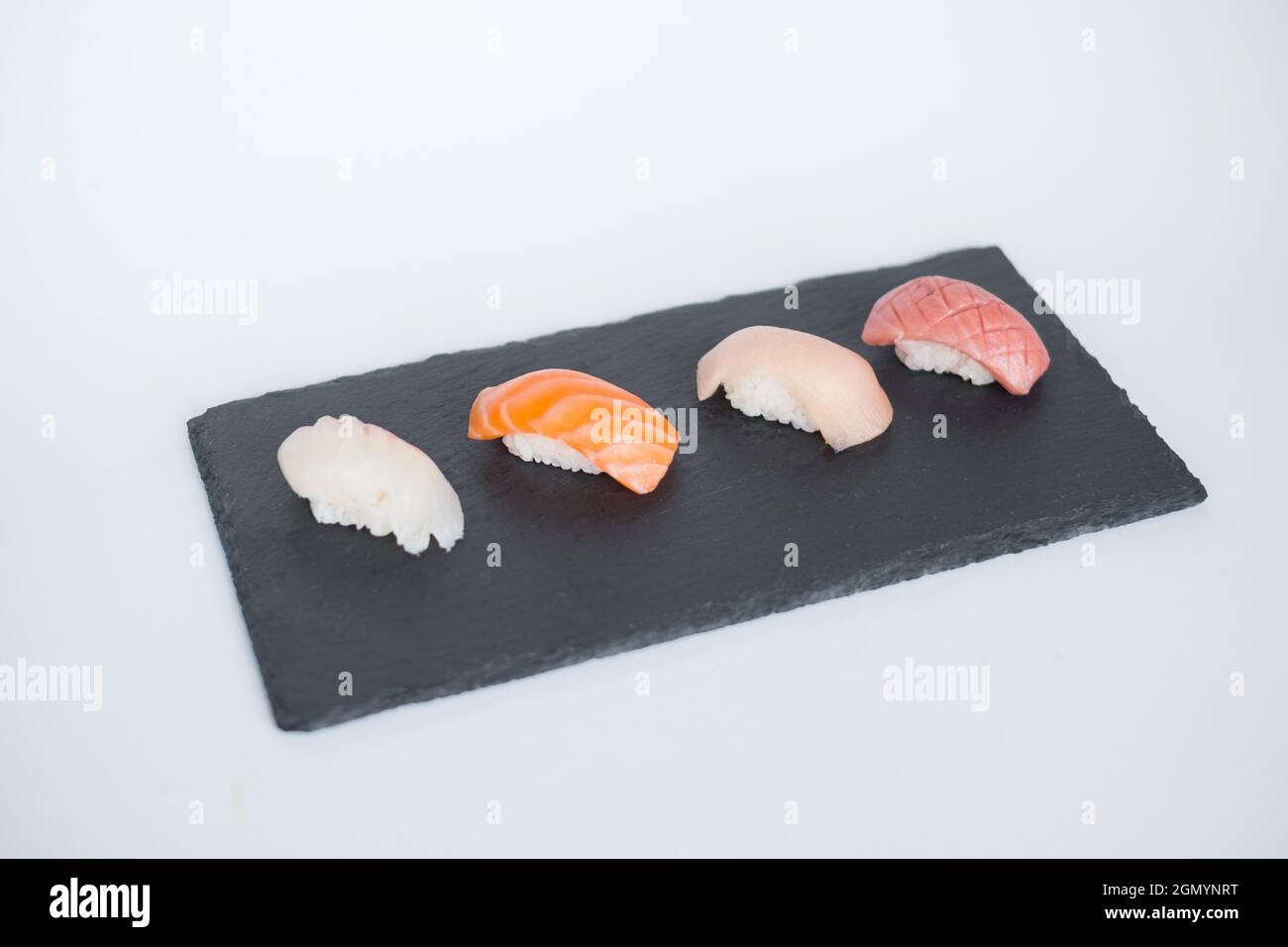 Four sushi nigiri served on the black slate on white background ...
