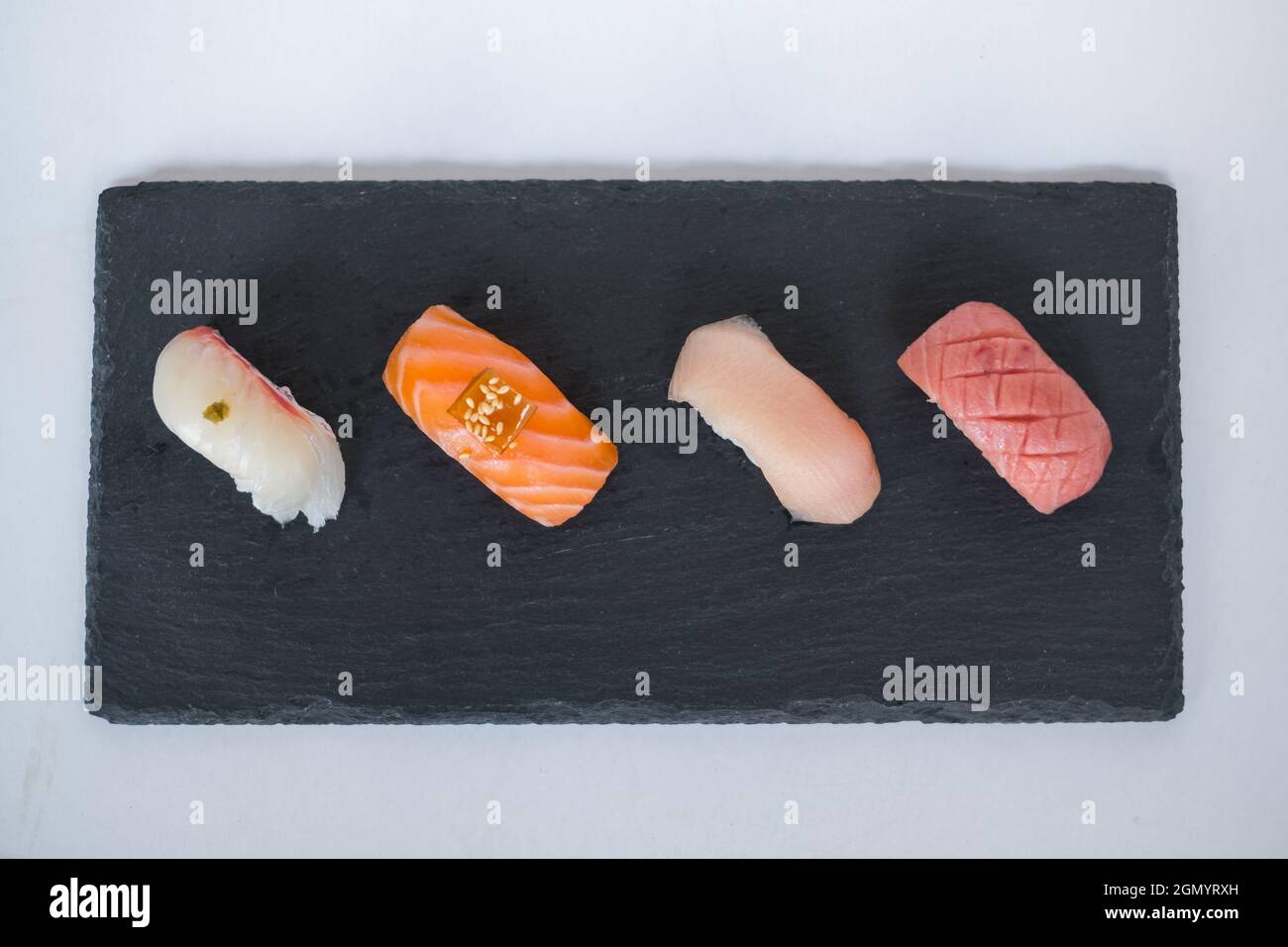 Four sushi nigiri served on the black slate on white background ...