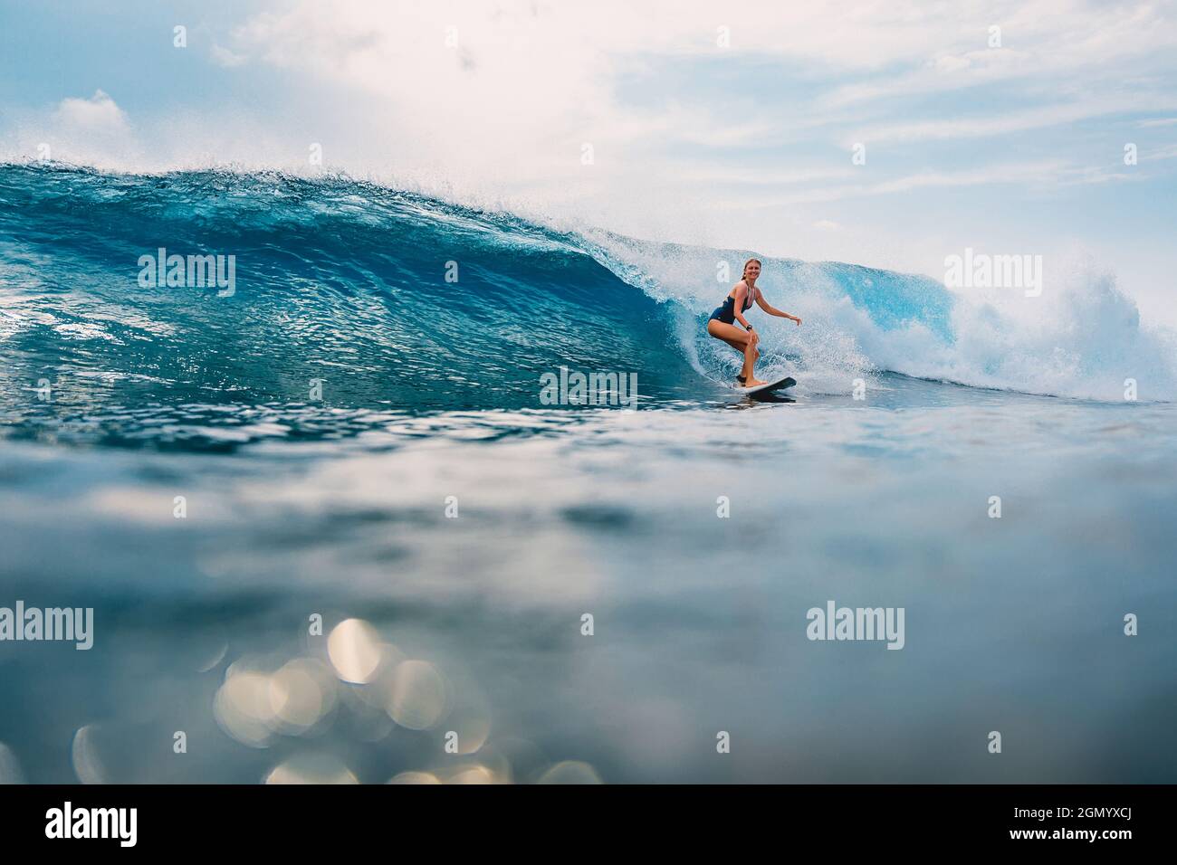 Surfer girl at surfboard on blue wave in tropical ocean. Sporty woman ...