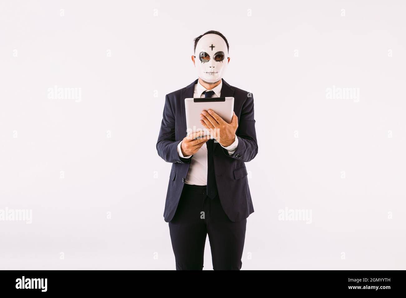 Man dressed in suit and tie, wearing a killer's mask with a cross on ...