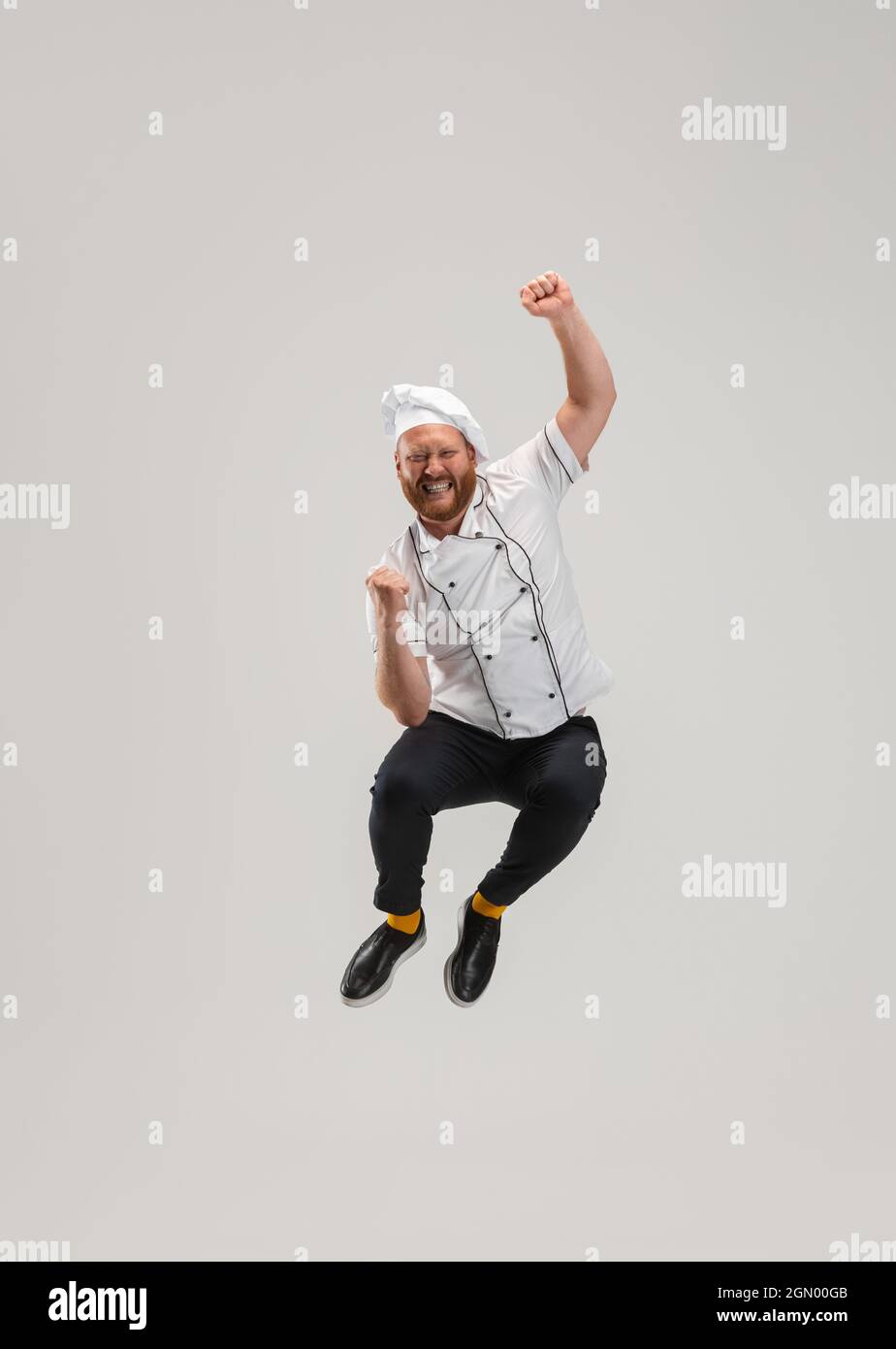One Caucasian bearded man, chef in uniform jumping high isolated on ...