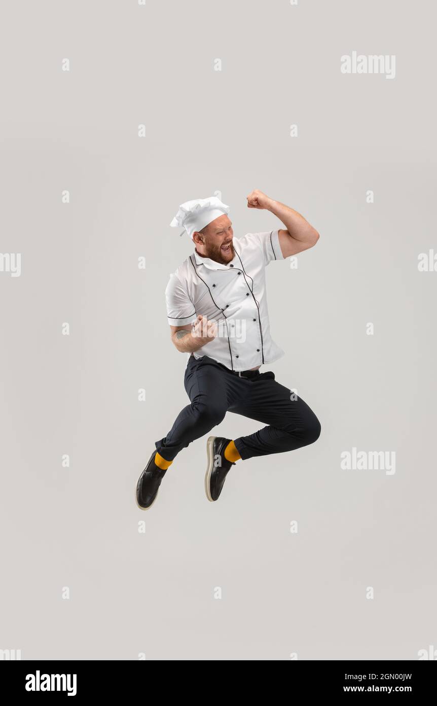 One Caucasian bearded man, chef in uniform jumping high isolated on ...