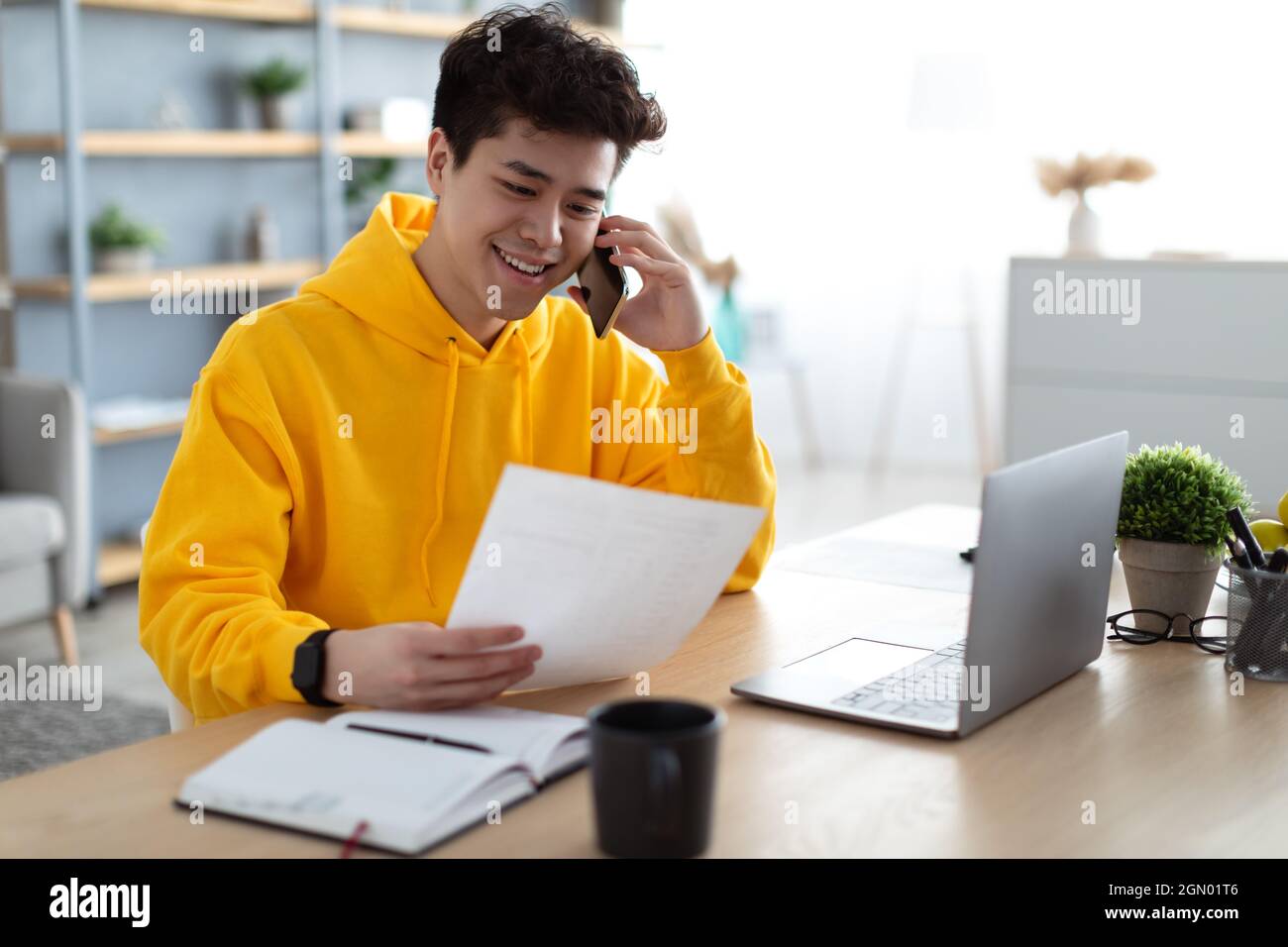 Guy holding paper reading report talking on phone at home Stock Photo ...