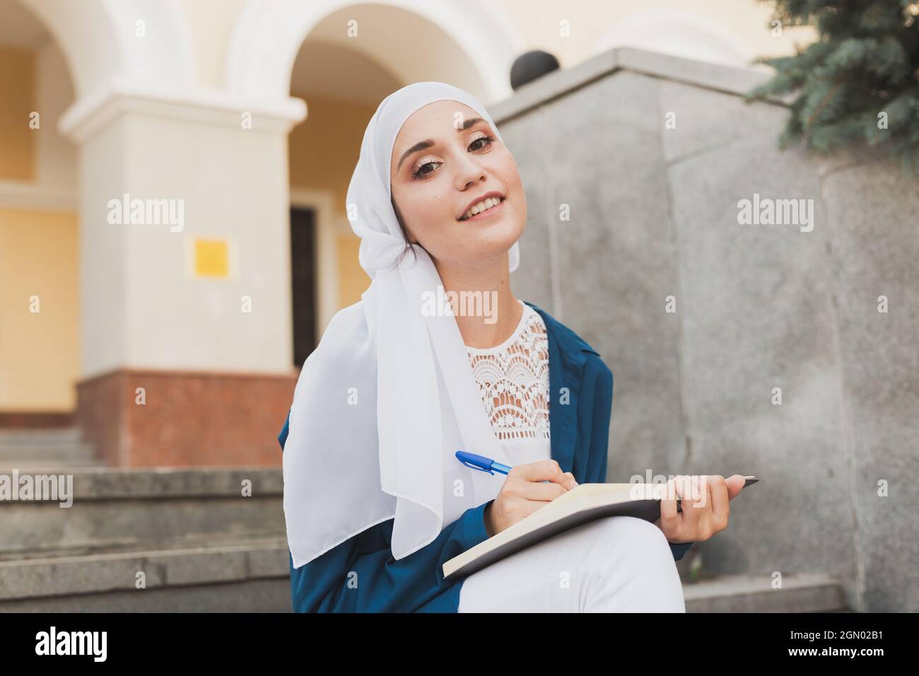 Female middle eastern college student sits on stairs in university ...
