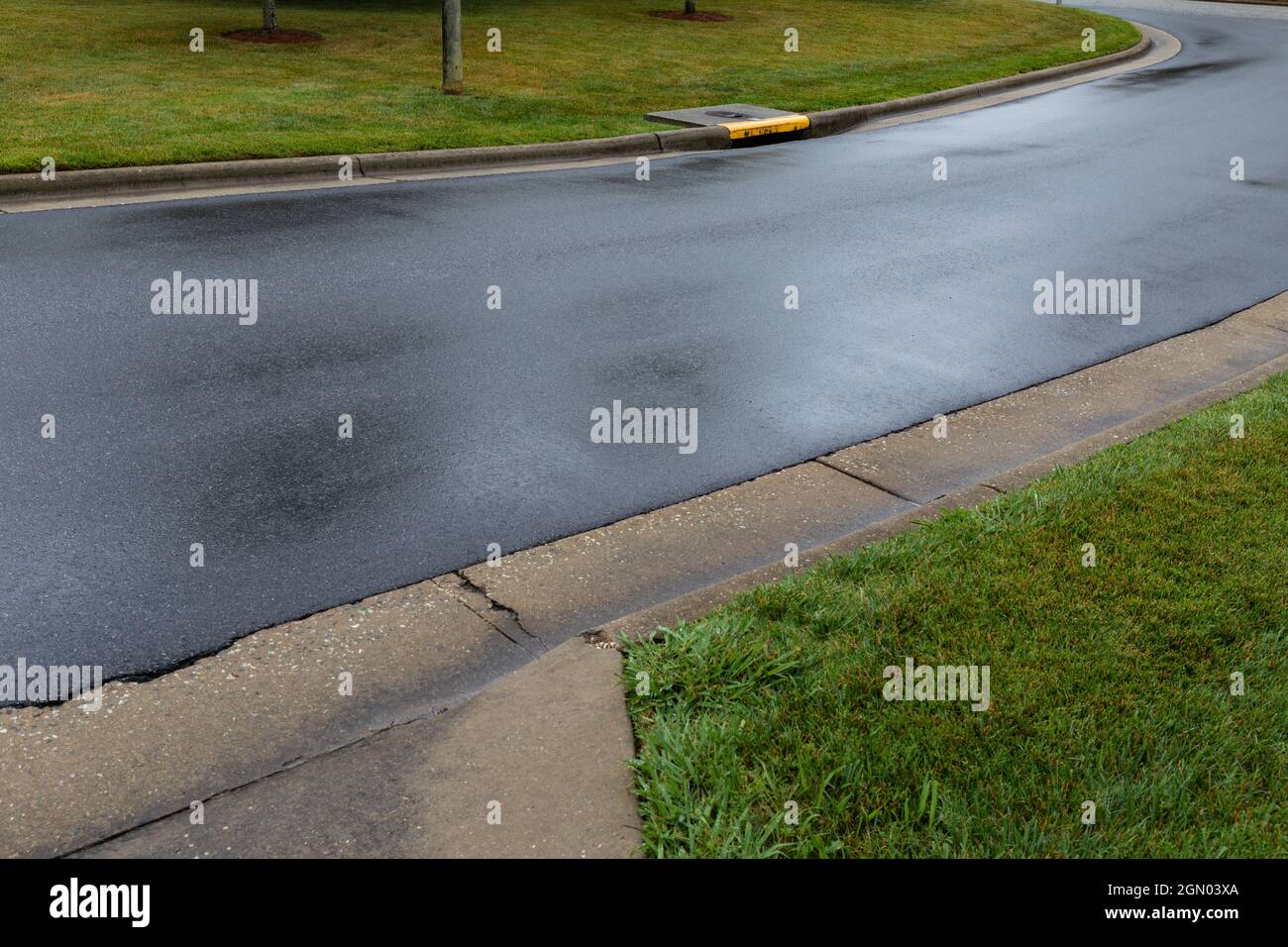 Diagonal view of a rain soaked street surface reflecting gray skies ...