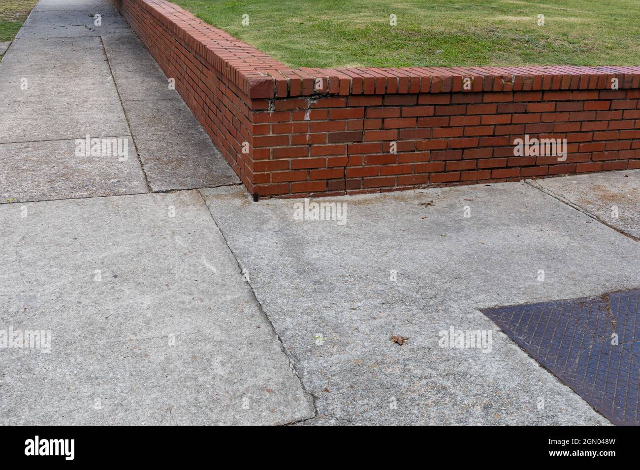 Low red brick retaining wall separating a grassy area from sidewalks ...