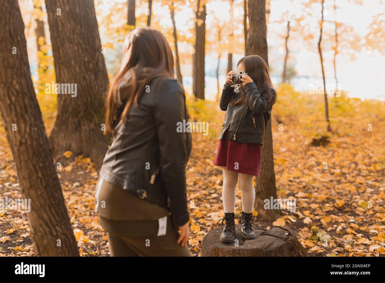 Child girl photographer takes pictures of a mother in the park in ...
