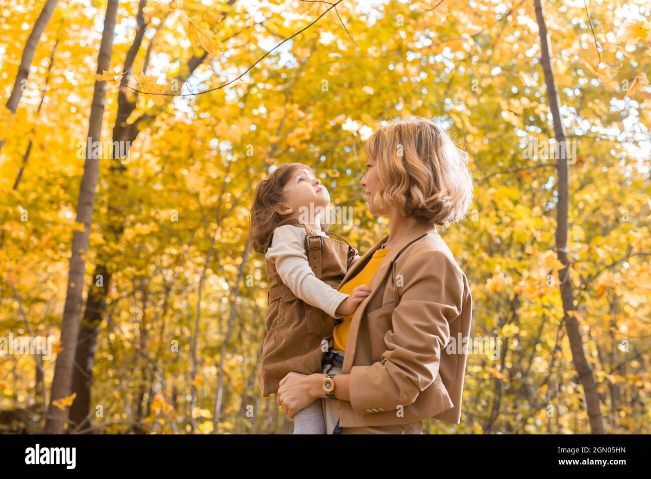 Young mother with her little daughter in an autumn park. Fall season ...