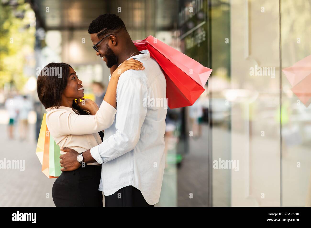 Happy afro couple hugging and holding shopping bags Stock Photo - Alamy