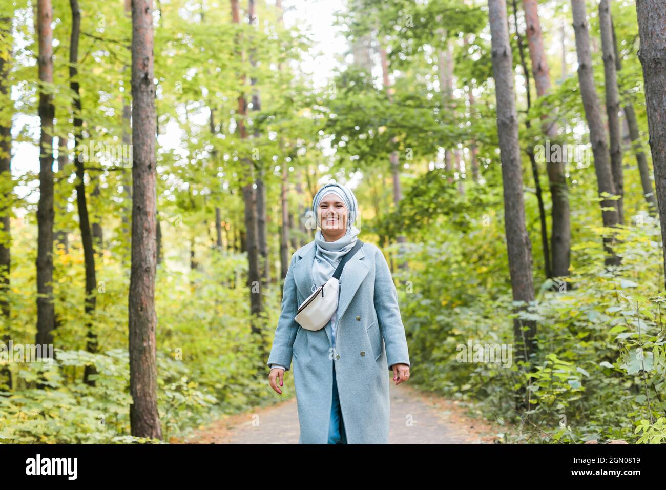 Islamic young woman wearing hijab standing on autumn park background ...