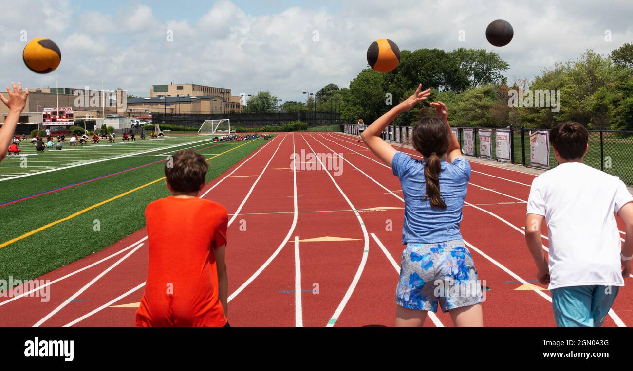 Rear view of Young teenagers throwing and chasing medicine balls down ...