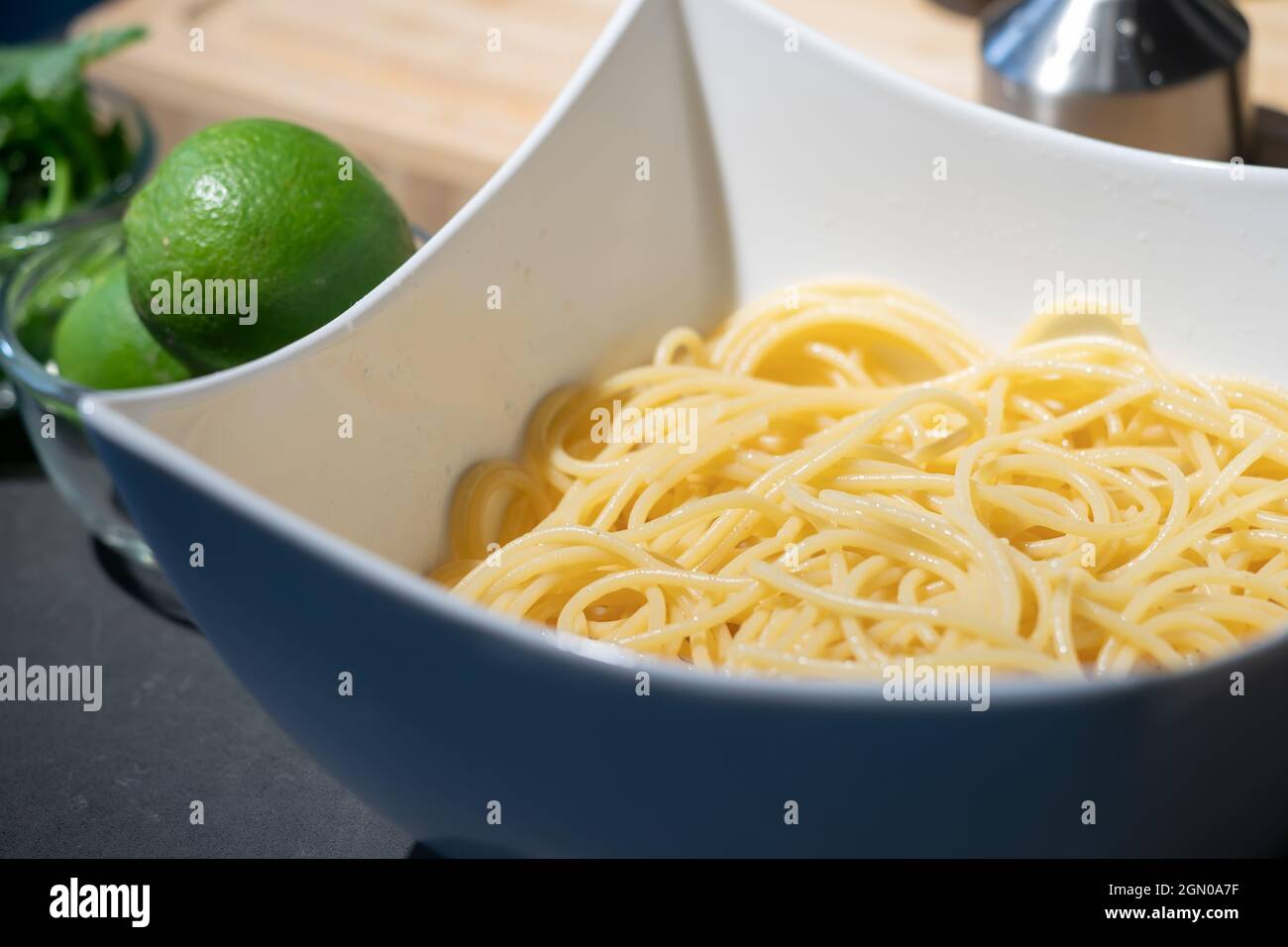 Cooked Spaghetti pasta in square white bowl on kitchen counter and ...
