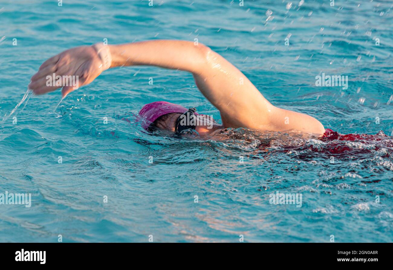 Close up of a female swiming in a pool with her arm raised in the air ...