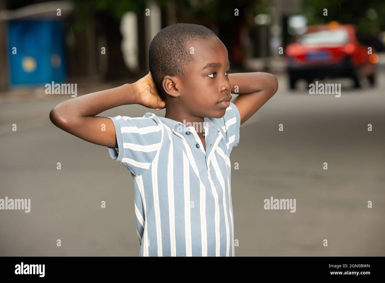 pretty little boy standing outside relaxes and stretches with arms and ...