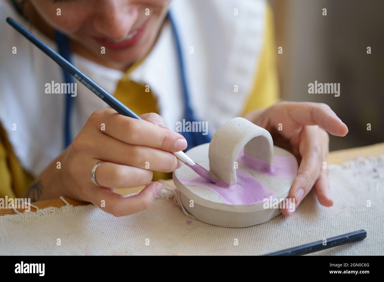 Artistic process in ceramics studio: woman ceramist artist painting ...